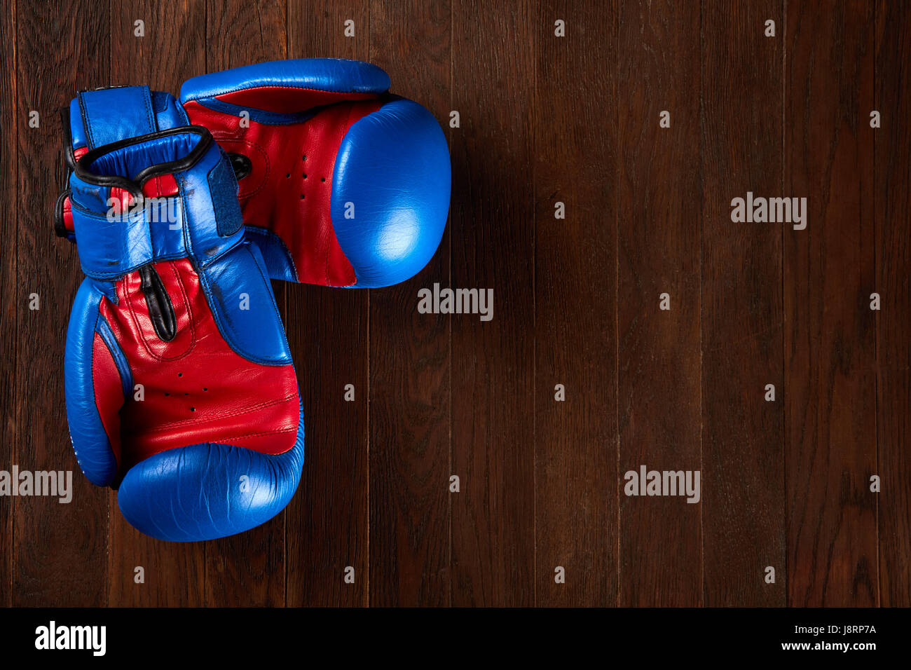 Pair of blue and red boxing gloves lying on the brown wooden table ...