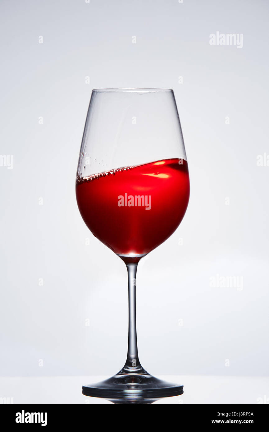 Fragile elegant wineglass of red wine standing against light background ...