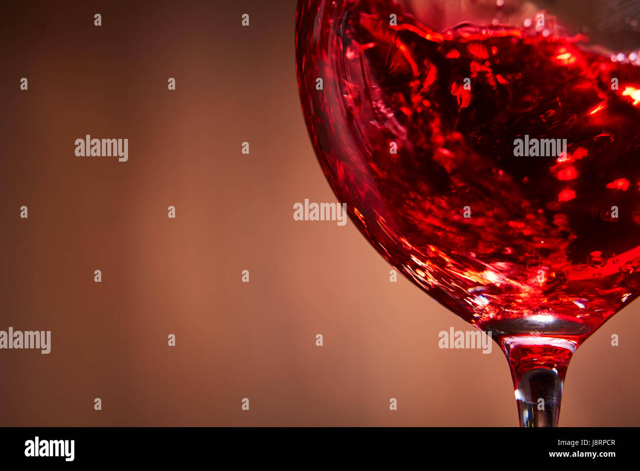 Close-up of the abstract splashing of the red wine in the fragile ...