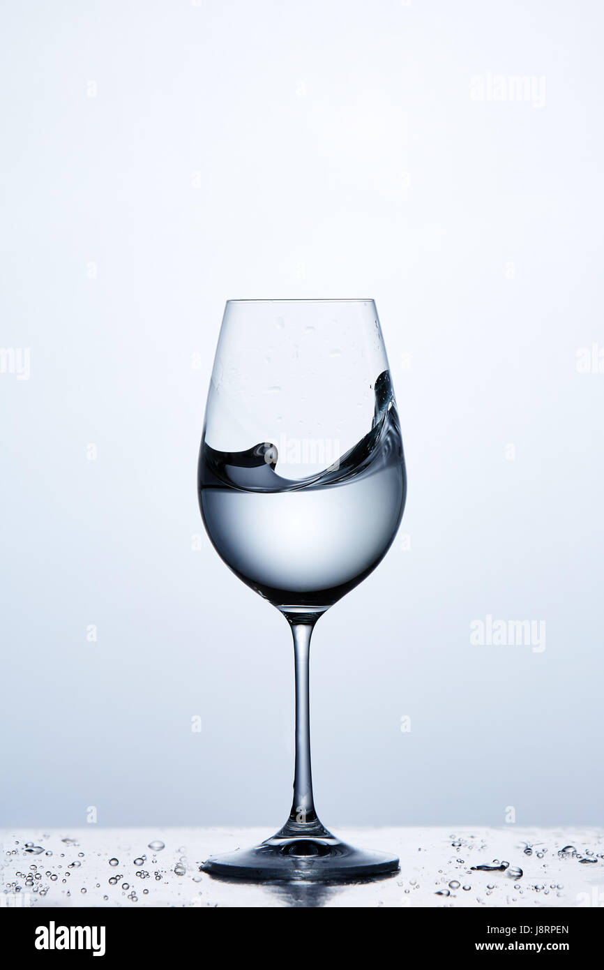 Transparent water wave in the wineglass while standing on the glass ...