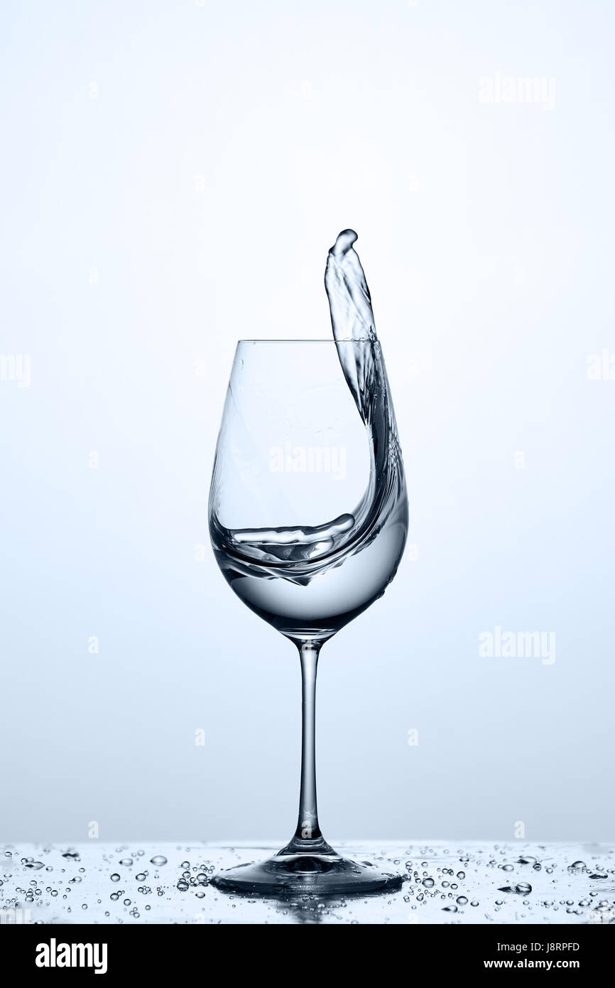Trasparent water splash out of wineglass while standing on the glass ...