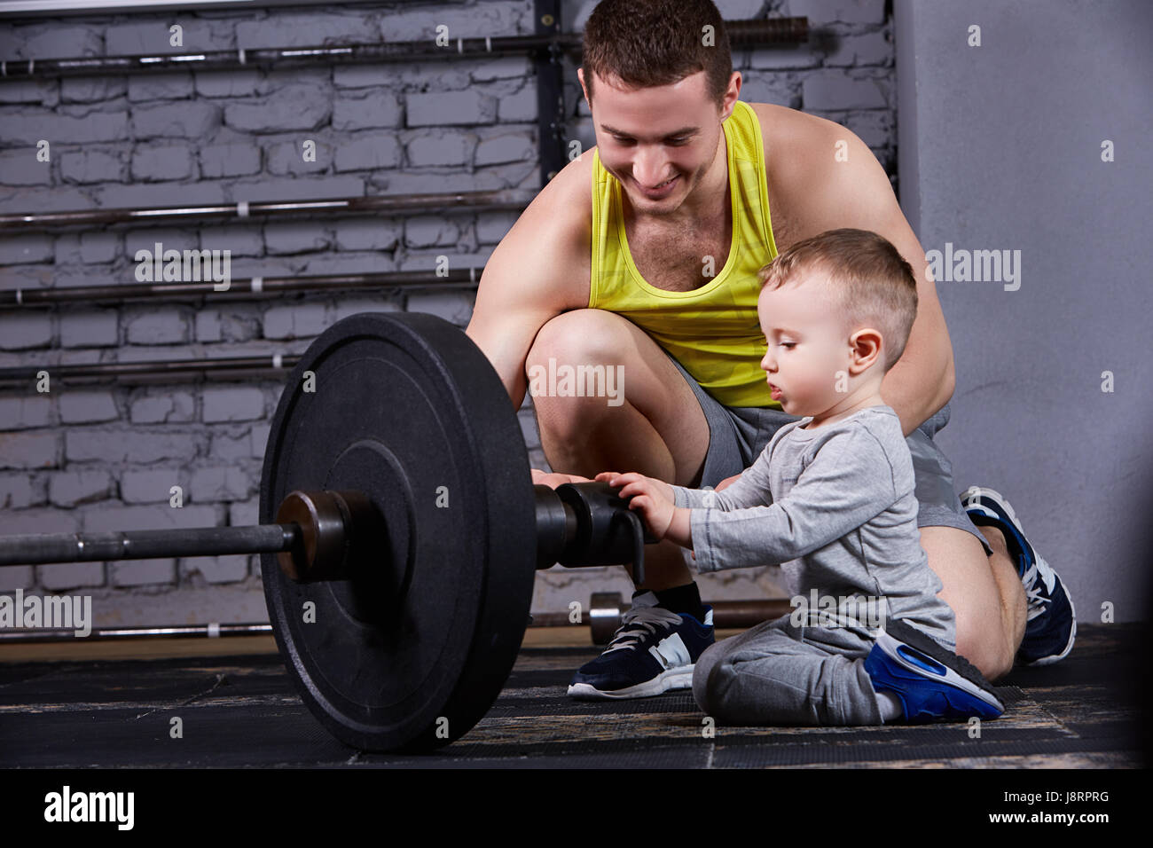 Young sporty father showing dumbbells for his little son and smiling ...