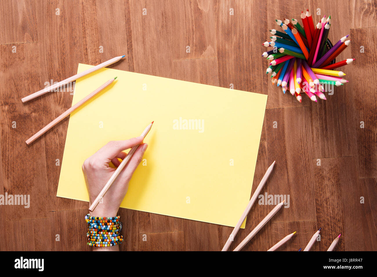 Girl hand drawing, blank yellow paper and colorful pencils on wooden ...