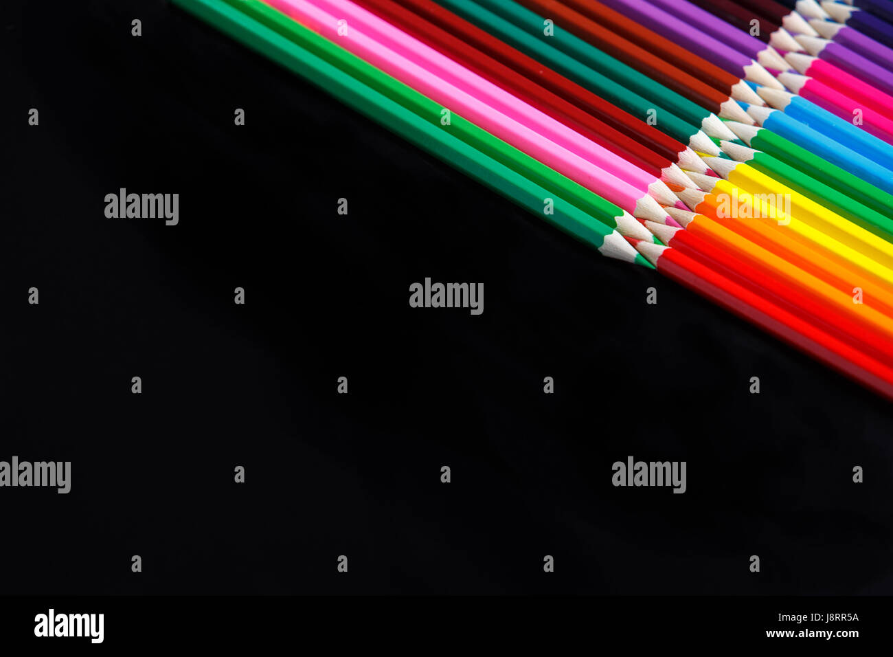 Colored pencils lie opposite isolated on the black background Stock ...