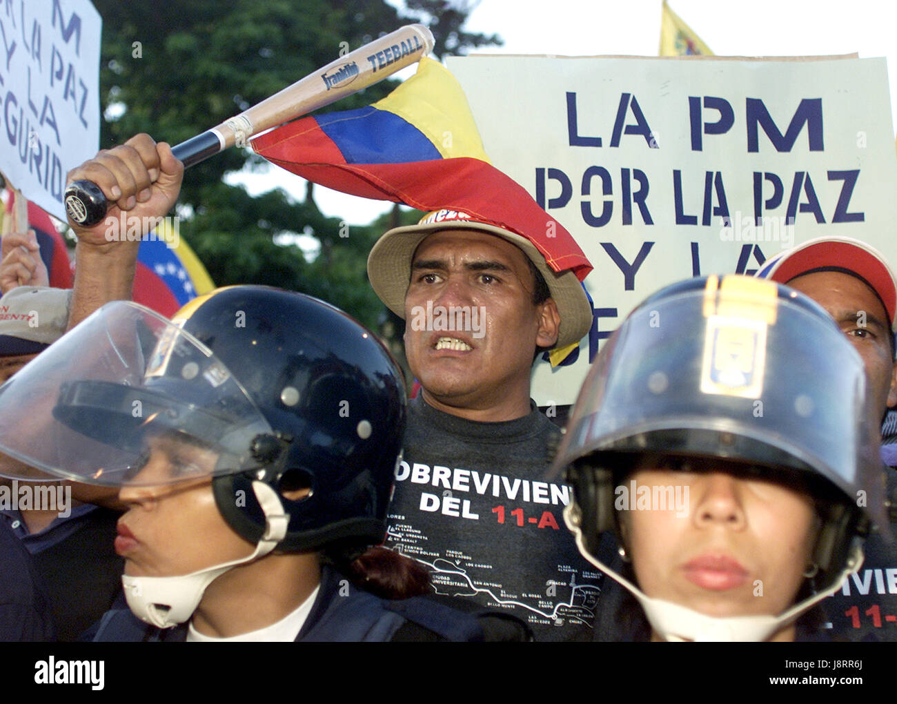 An opposition member waves a bat behind a police line in Caracas ...