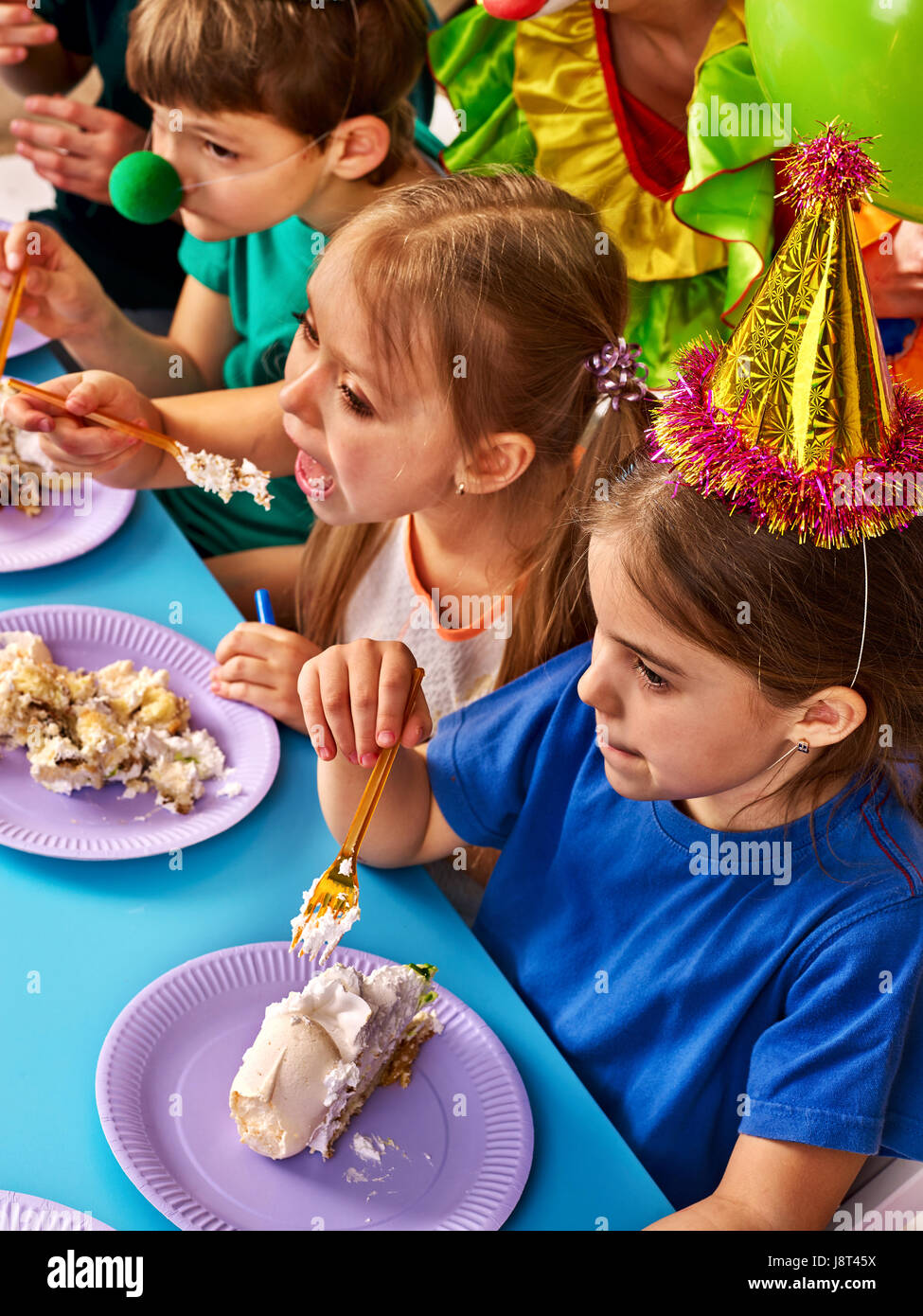 Birthday child clown eating cake with boy together. Kid with messy face ...
