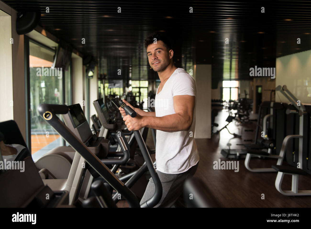 Muscular Man Doing Aerobics Elliptical Walker In Modern Fitness Center ...