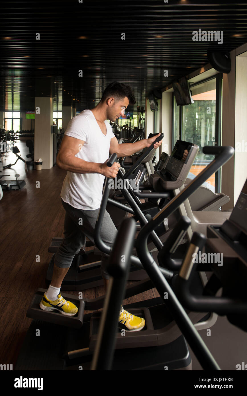 Muscular Man Doing Aerobics Elliptical Walker In Modern Fitness Center ...