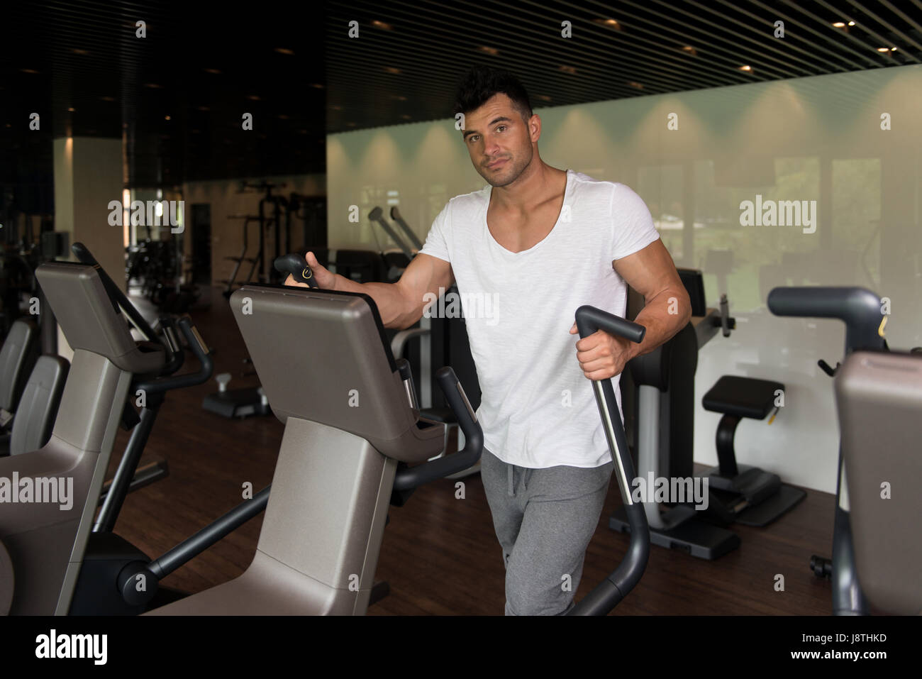 Muscular Man Doing Aerobics Elliptical Walker In Modern Fitness Center ...