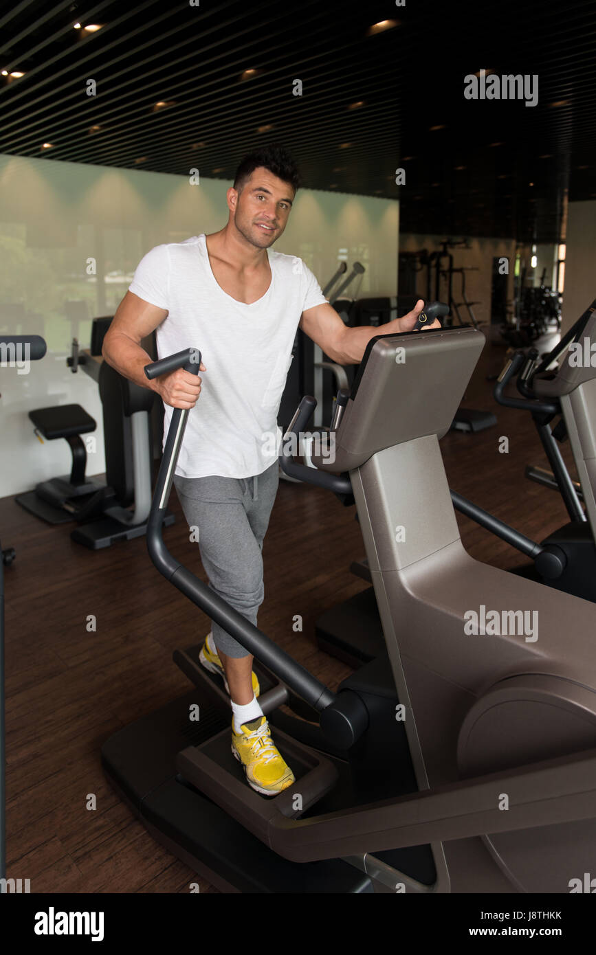 Muscular Man Doing Aerobics Elliptical Walker In Modern Fitness Center ...