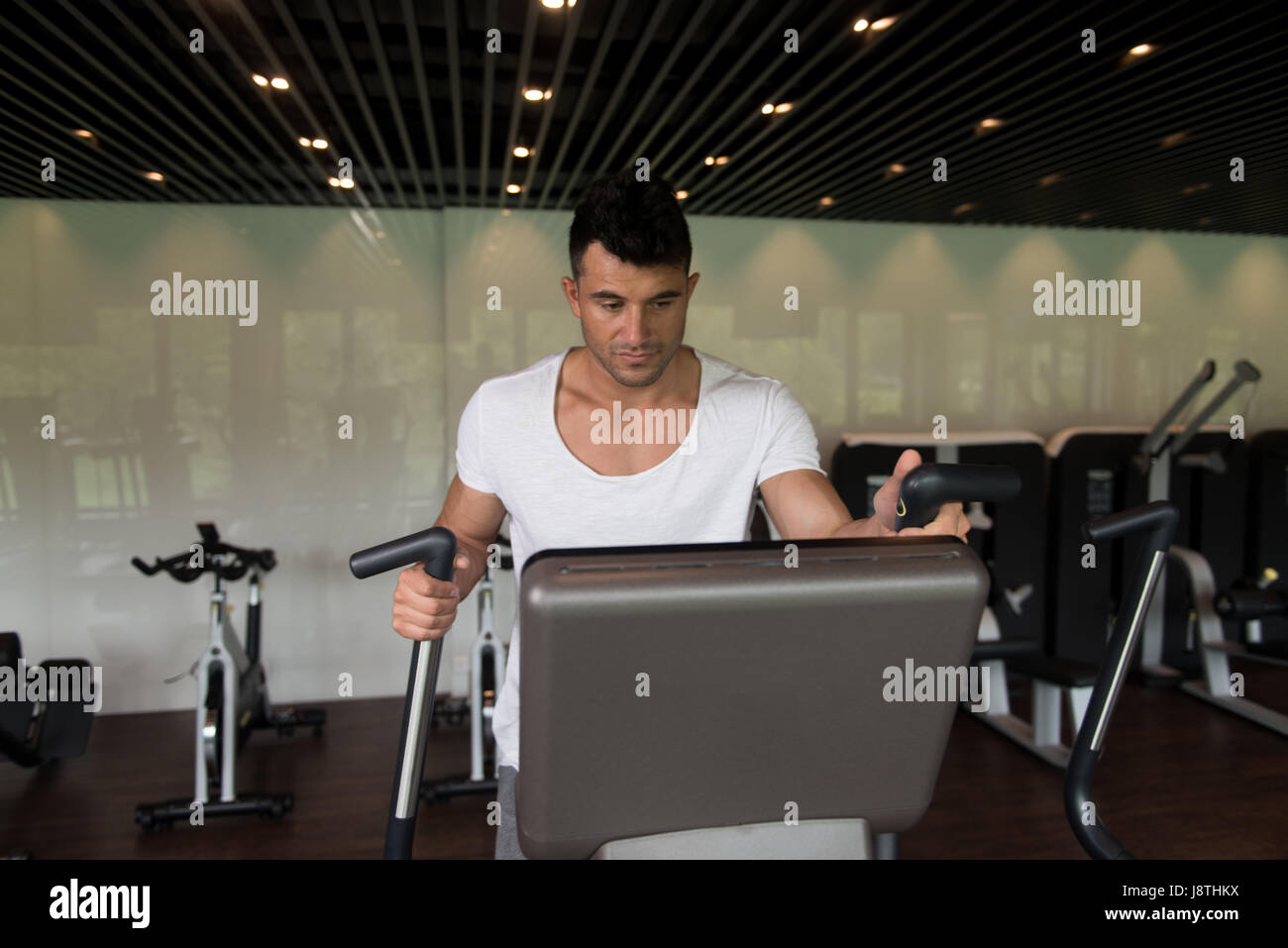 Muscular Man Doing Aerobics Elliptical Walker In Modern Fitness Center ...