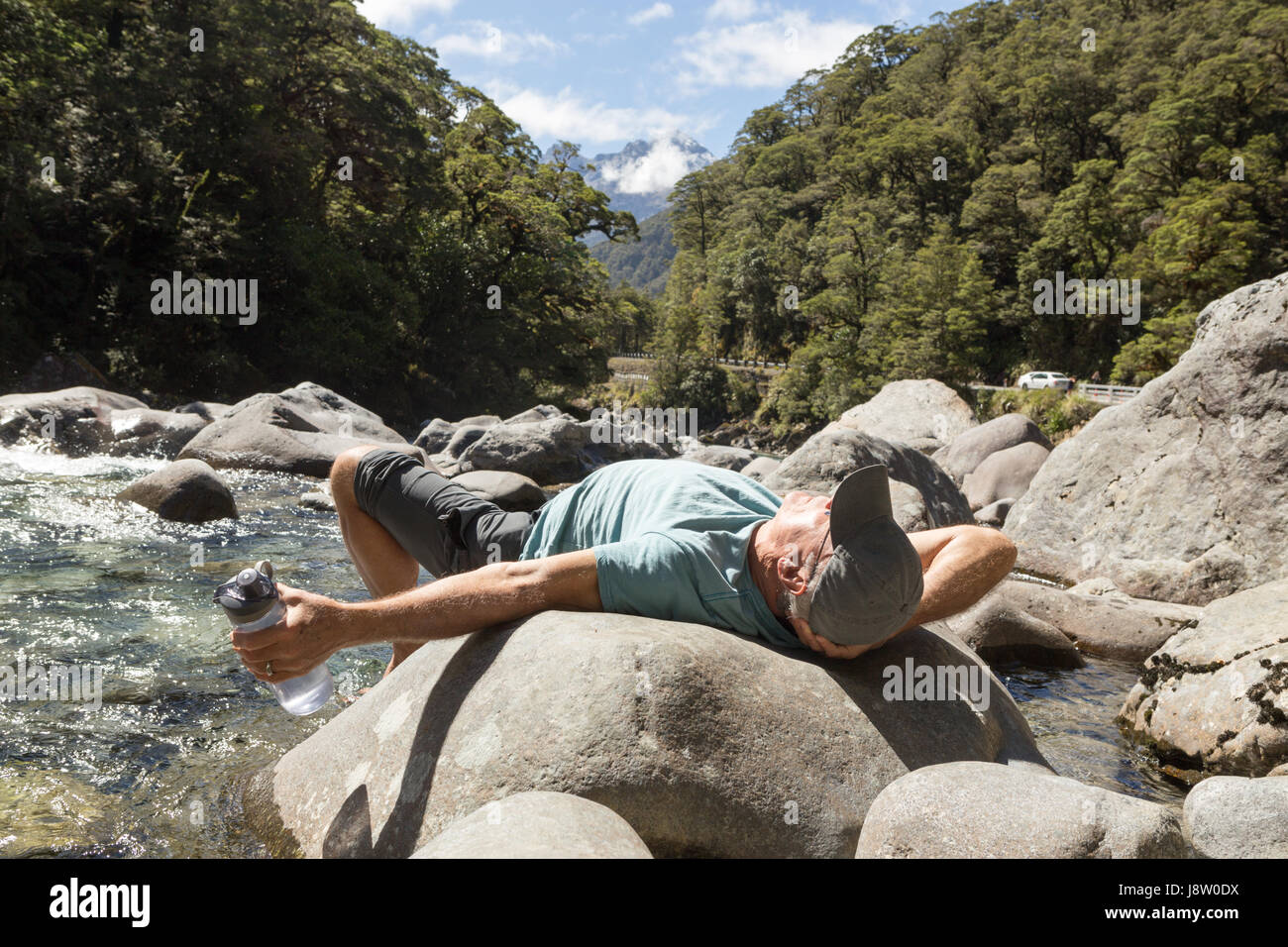 senior man resting on a rock by a river in Fiordland New Zealand Stock ...