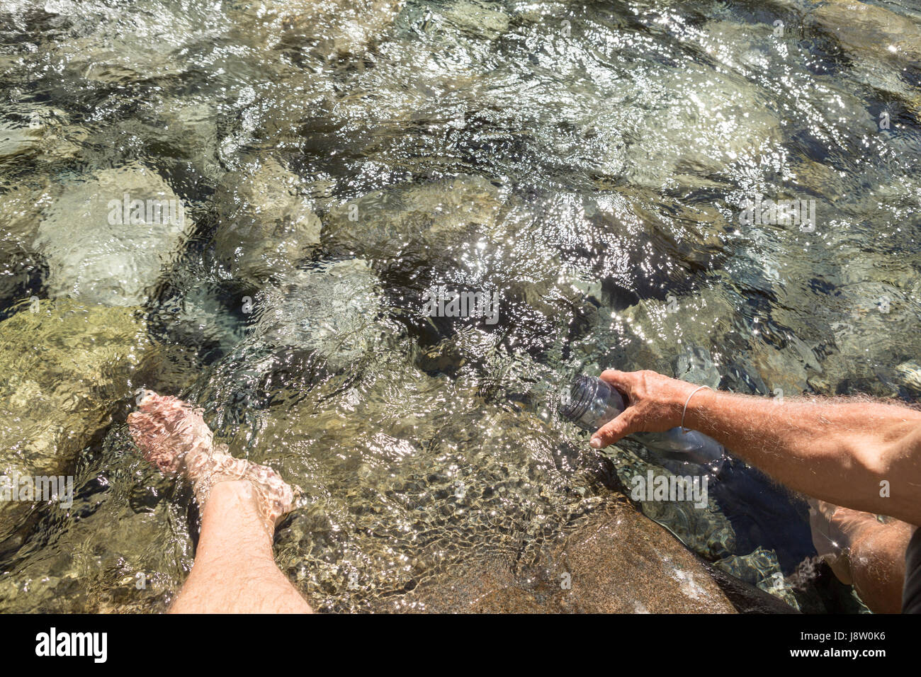 filling a water bottle in a clear stream in Fiordland New Zealand Stock ...