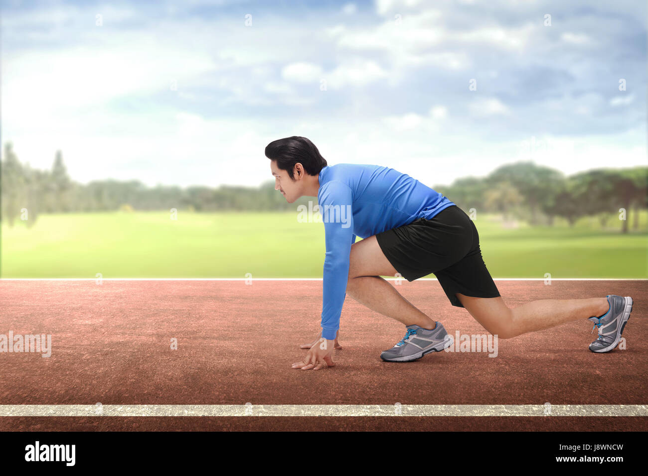 Young asian runner in start position ready to running on race track ...