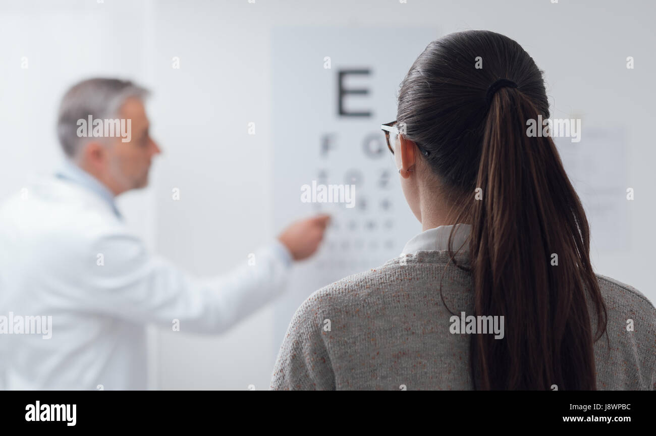 Woman reading the eye chart, the ophthalmologist is pointing at one ...