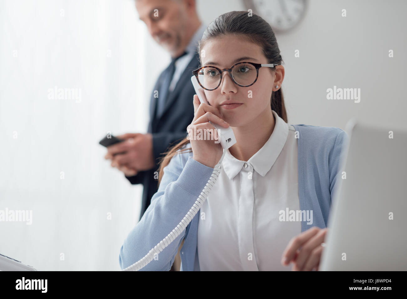 Young efficient secretary working in the office, she is answering phone ...