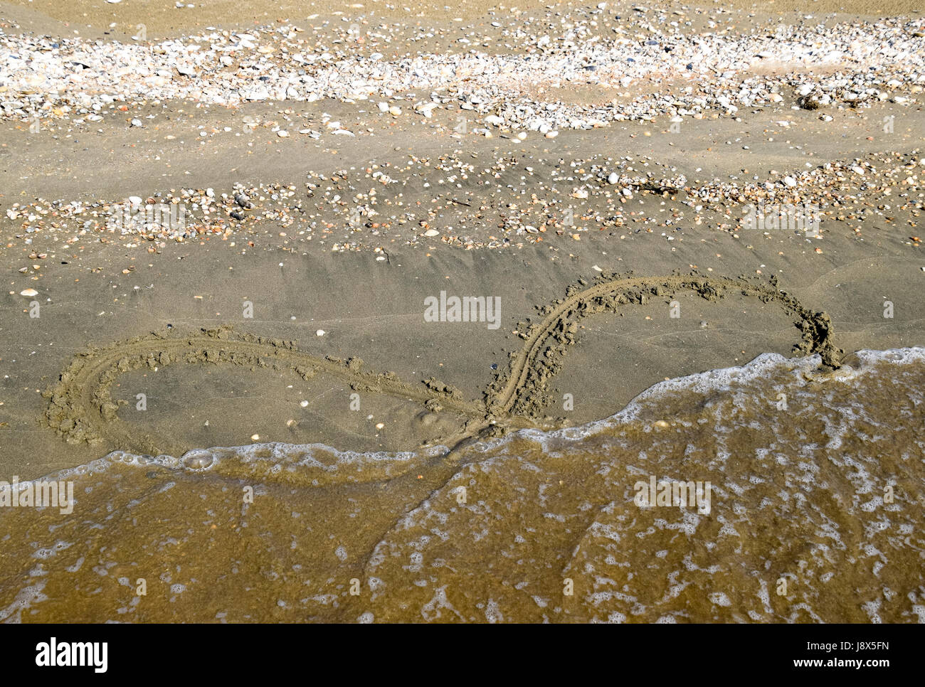 The sign of infinity on the sea. Coastal sand on the beach. The symbol ...