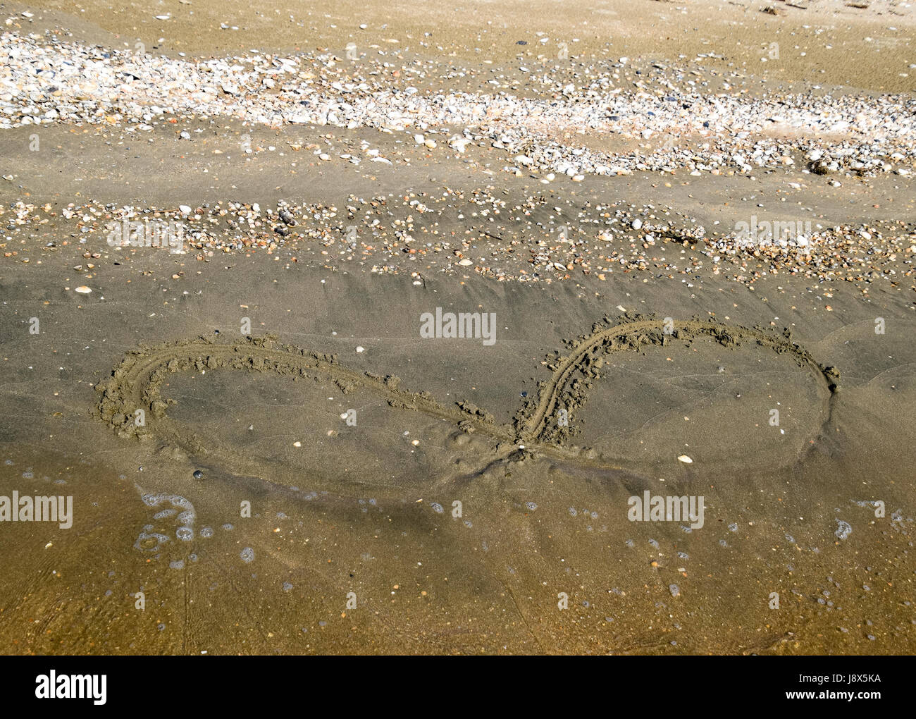 The sign of infinity on the sea. Coastal sand on the beach. The symbol ...