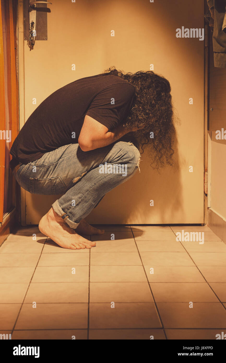 Man crouching on a floor tiles, sad, depressed and lonely, crying Stock ...