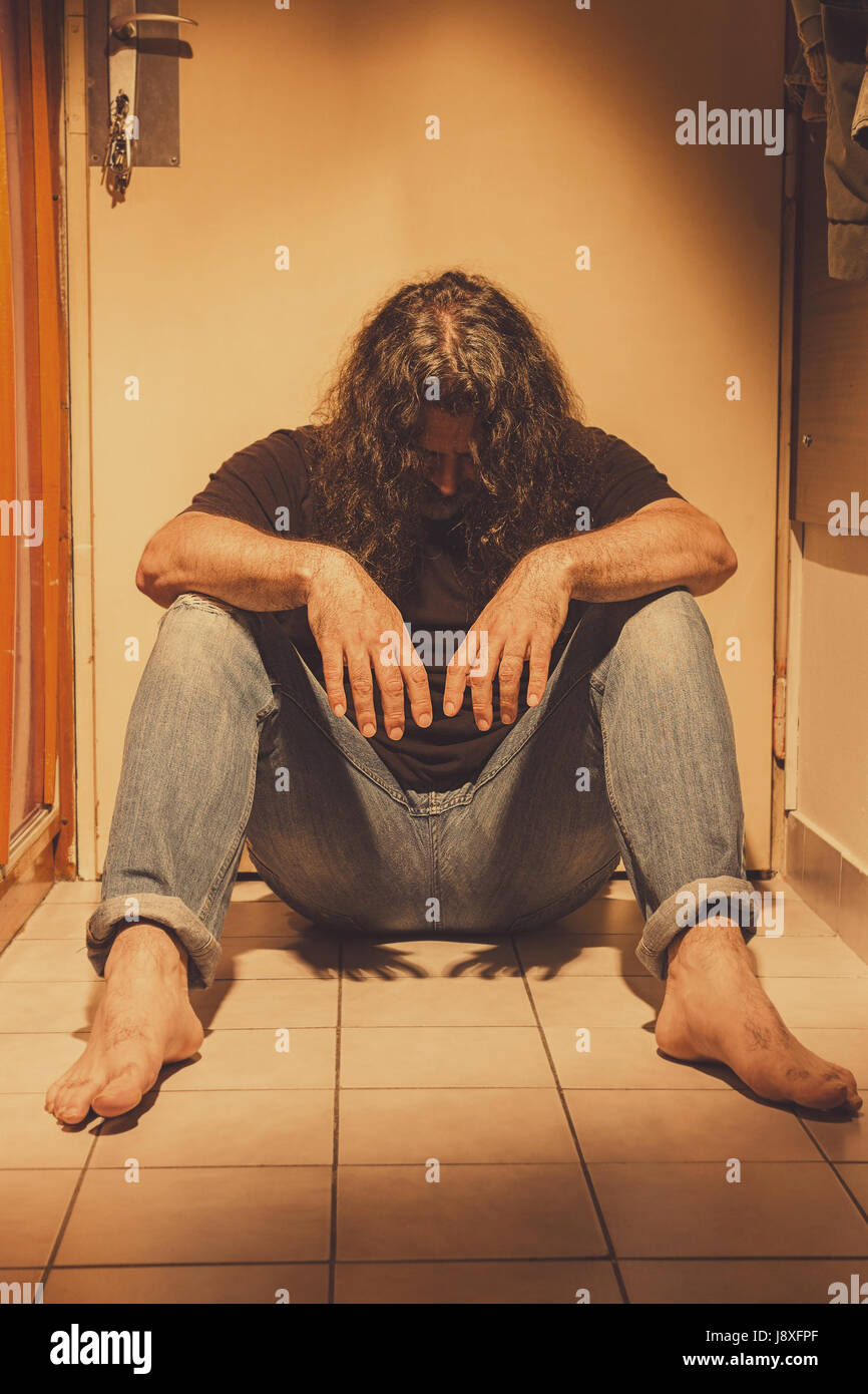 Man sitting on a floor tiles, sad, depressed and lonely Stock Photo - Alamy