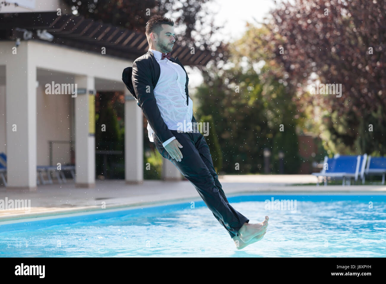 Handsome man jumping in the pool smiling and having fun Stock Photo - Alamy