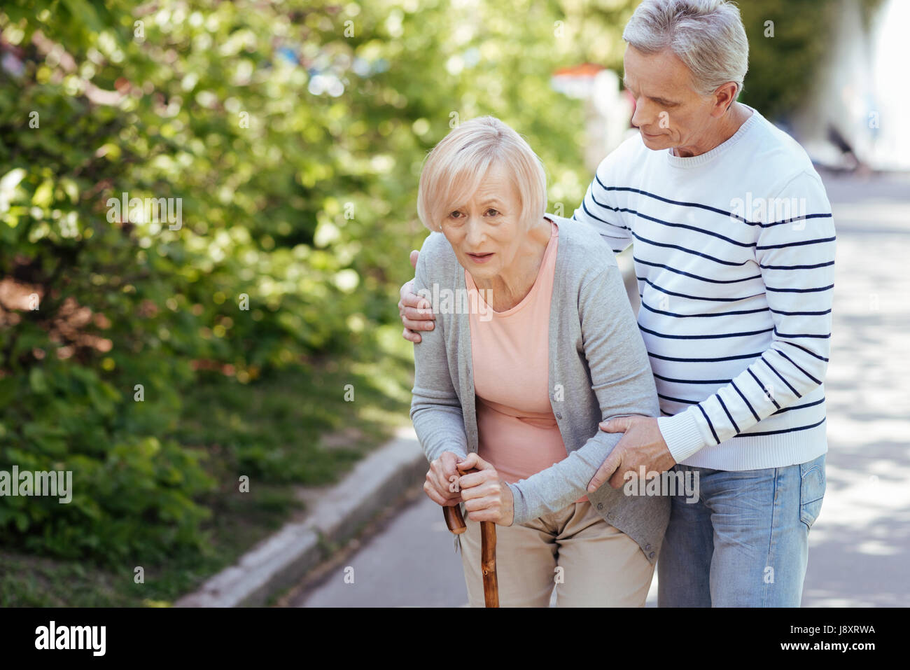 Caring senior husband helping ill wife in the park Stock Photo - Alamy