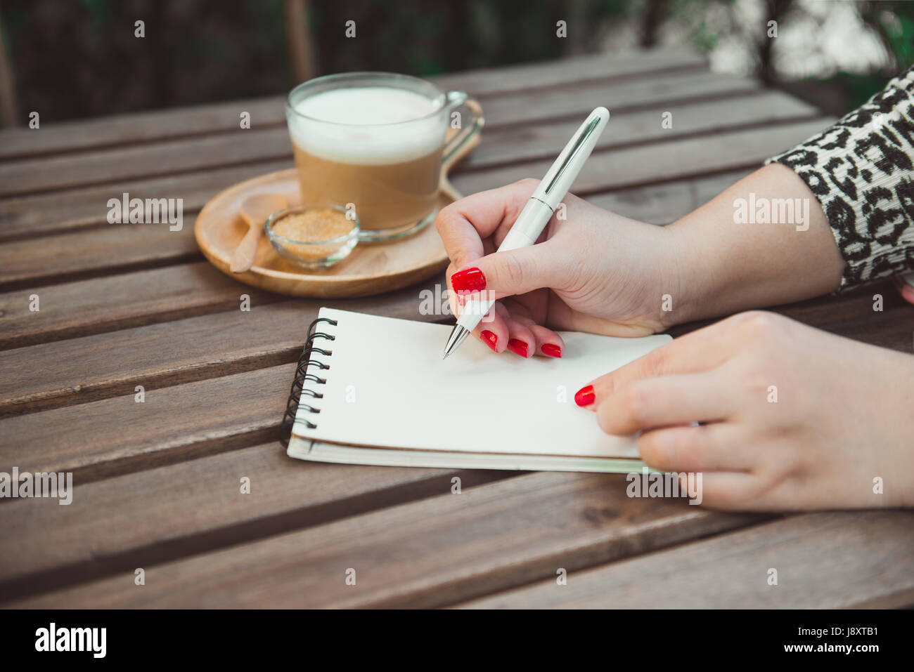 Woman's hands writing on notebook , hot coffee and vintage wooden table ...
