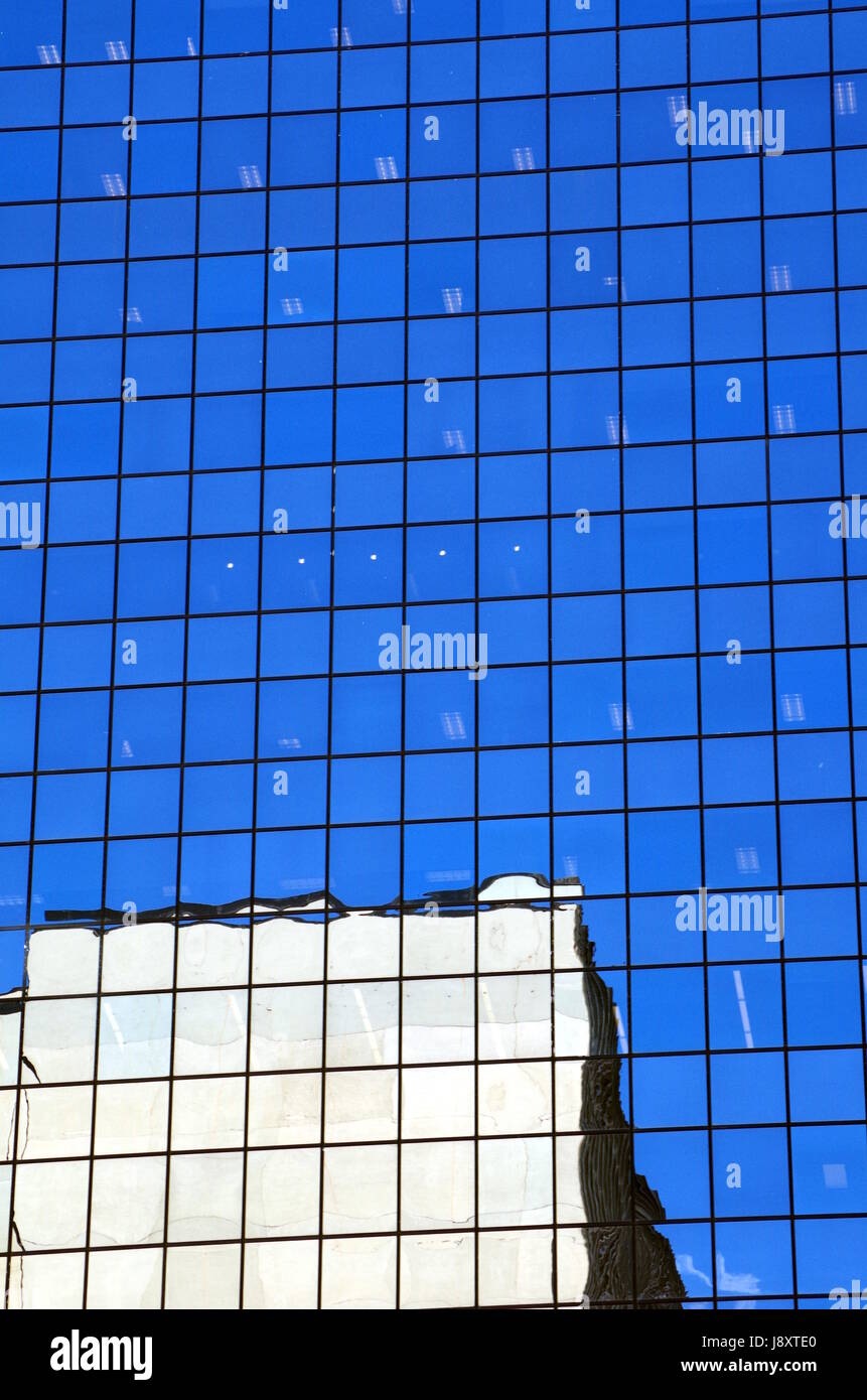 Office building windows reflecting blue sky and another office building ...