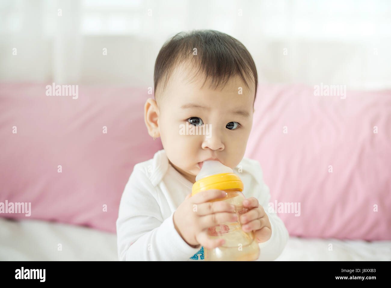 Sweet baby girl sucking milk in bottle at home Stock Photo - Alamy