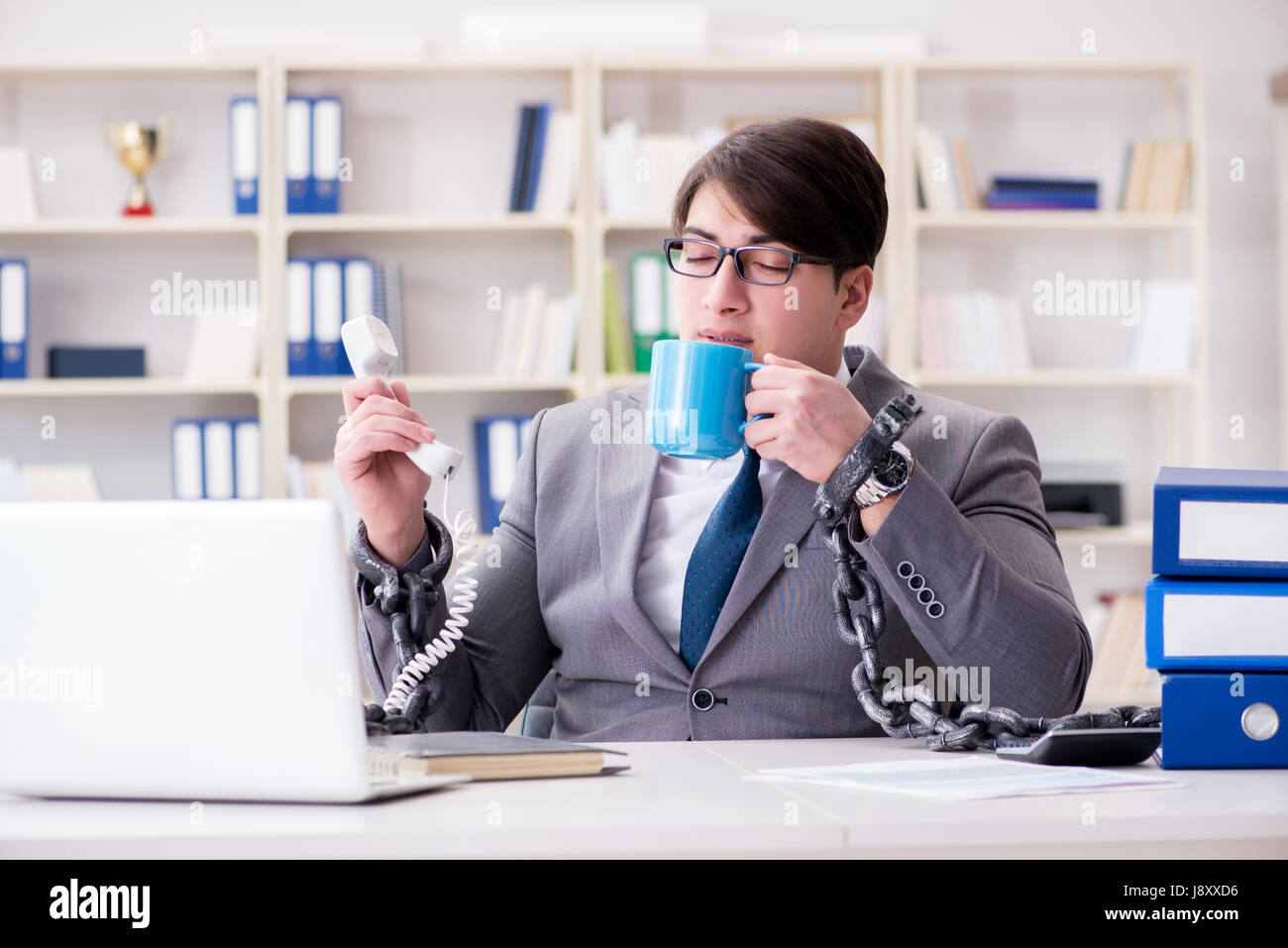 Businessman tied with chains to his work Stock Photo - Alamy