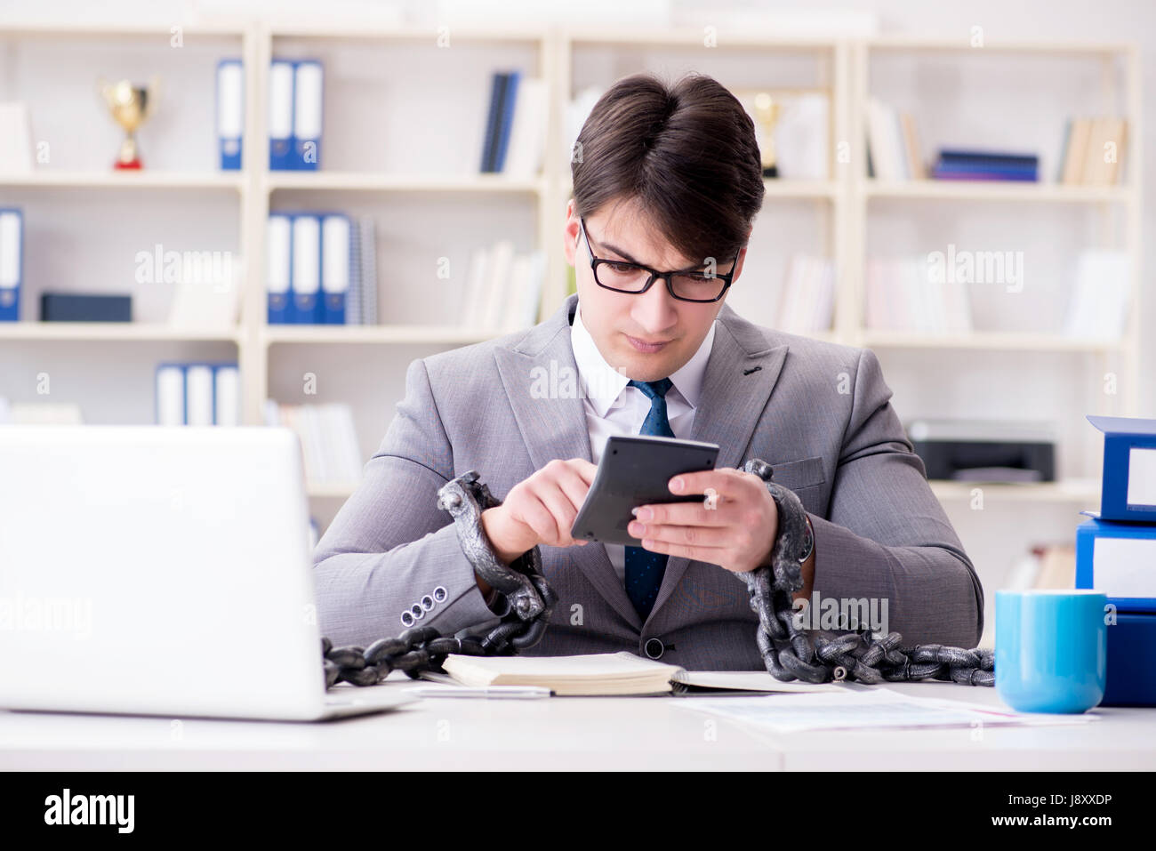 Businessman tied with chains to his work Stock Photo - Alamy
