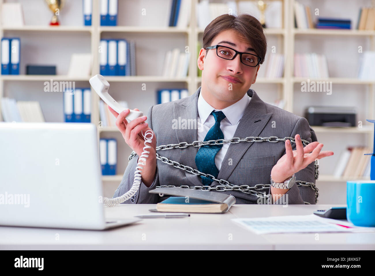 Businessman tied with chains to his work Stock Photo - Alamy