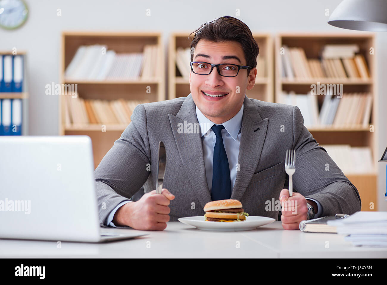 Hungry funny businessman eating junk food sandwich Stock Photo - Alamy