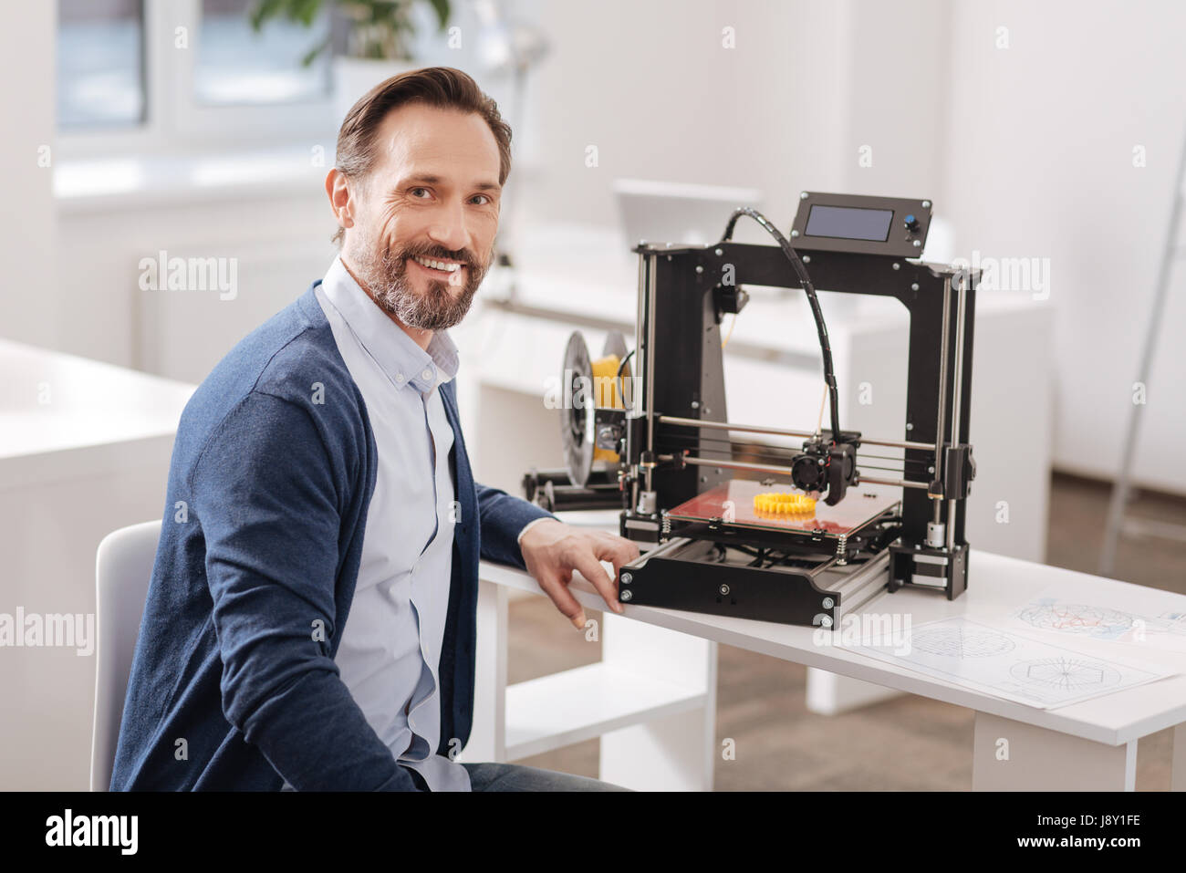Handsome delighted man sitting near the 3d printer Stock Photo - Alamy