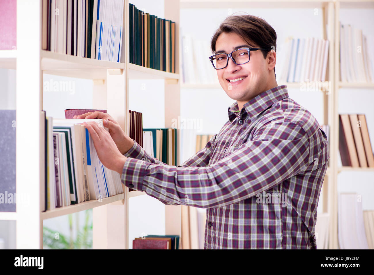 Young student looking for books in college library Stock Photo - Alamy
