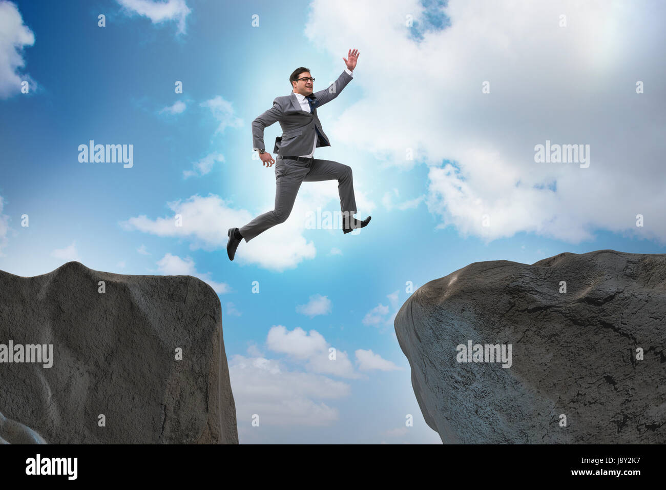 Ambitious businessman jumping over the cliff Stock Photo - Alamy