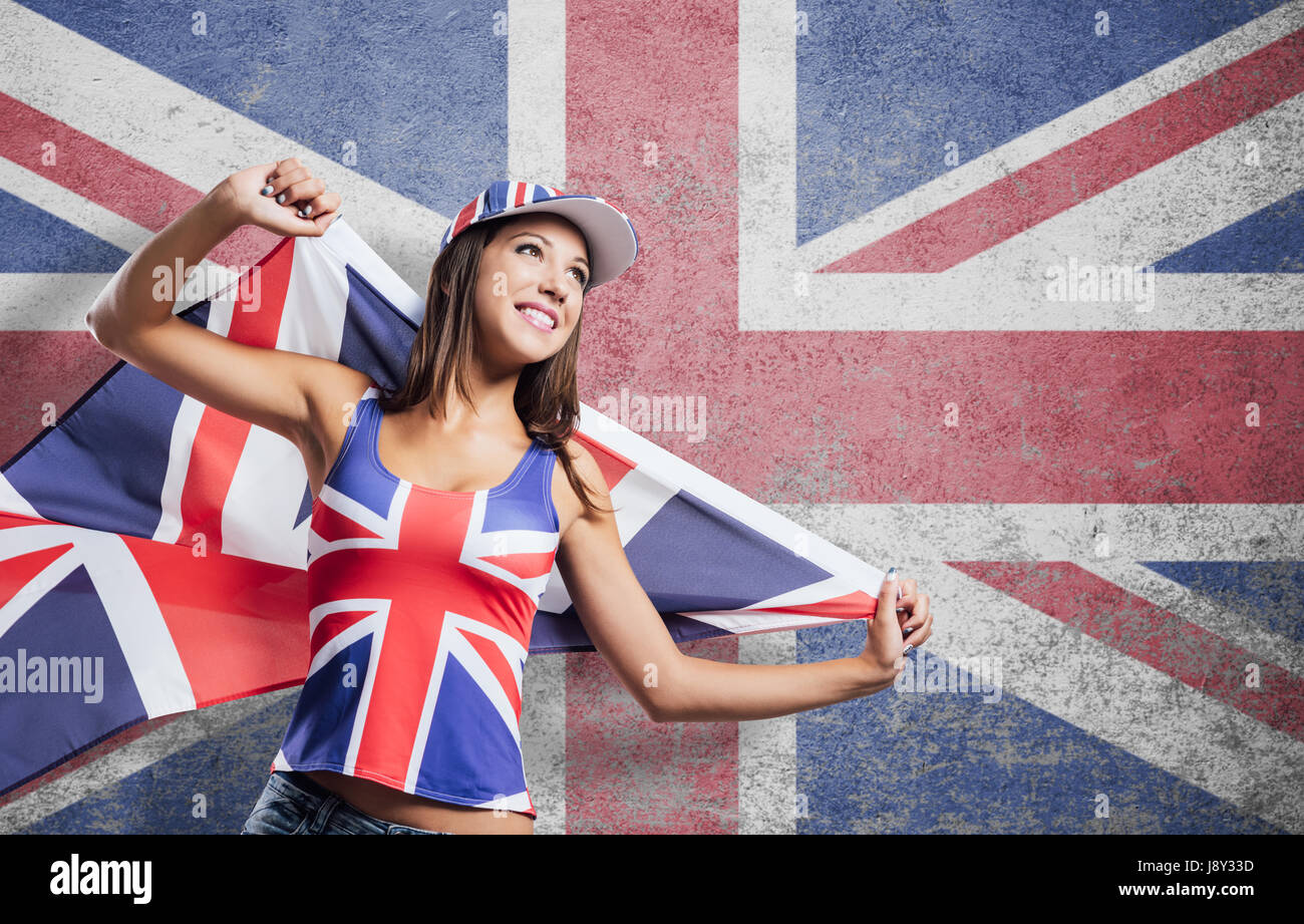 Cheerful cute English girl holding a flag, wearing a tank top and a cap ...