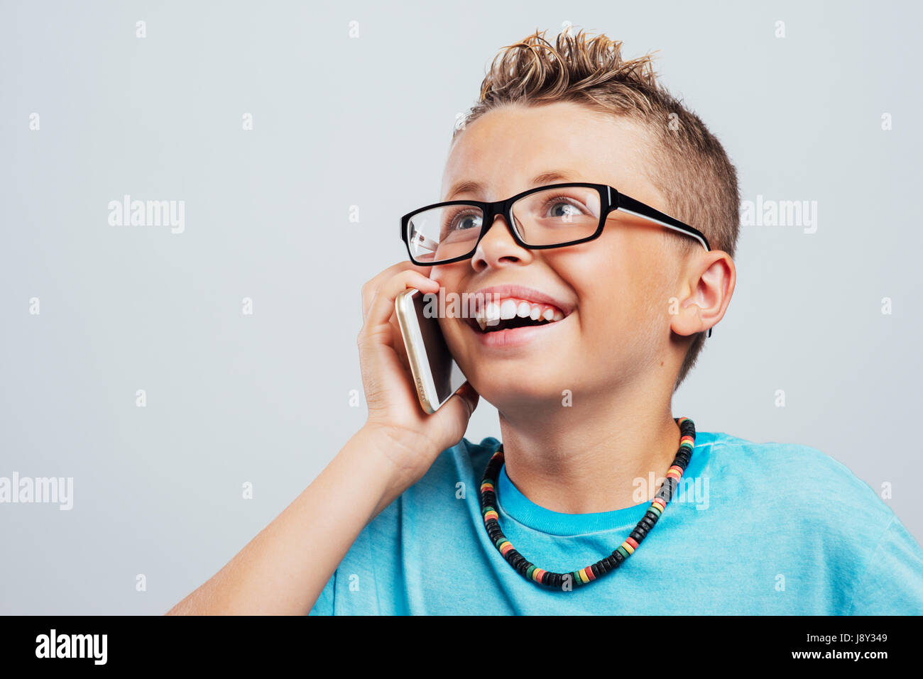 Smiling young boy having a phone call with his touch screen smart phone ...