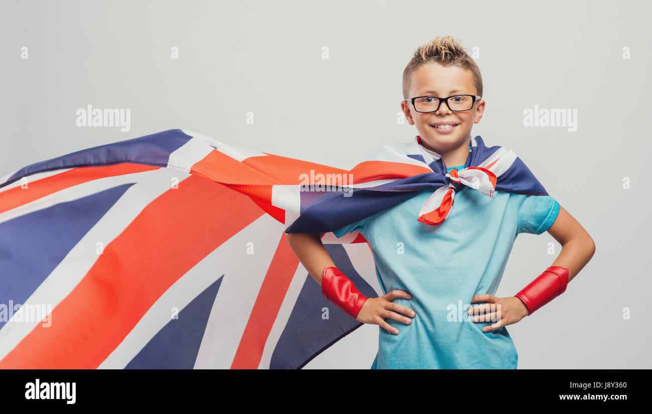 Cute smiling superhero boy posing with arms akimbo and wearing a ...