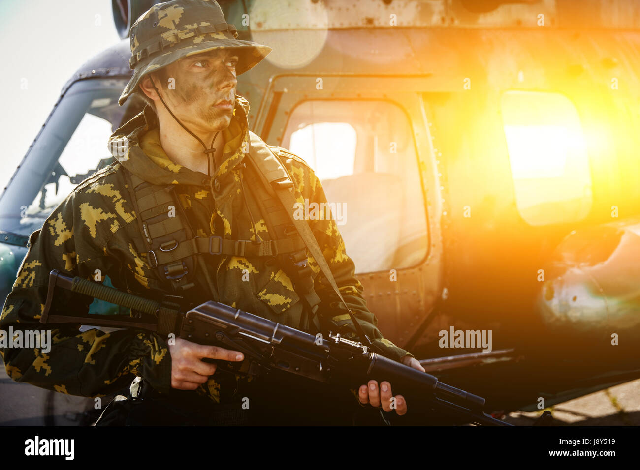 Photo of a soldier with an automatic rifle at a helicopter Stock Photo ...