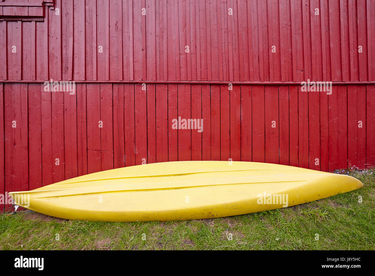 Yellow kayak over a red wooden cabin facade. Adventure sports ...