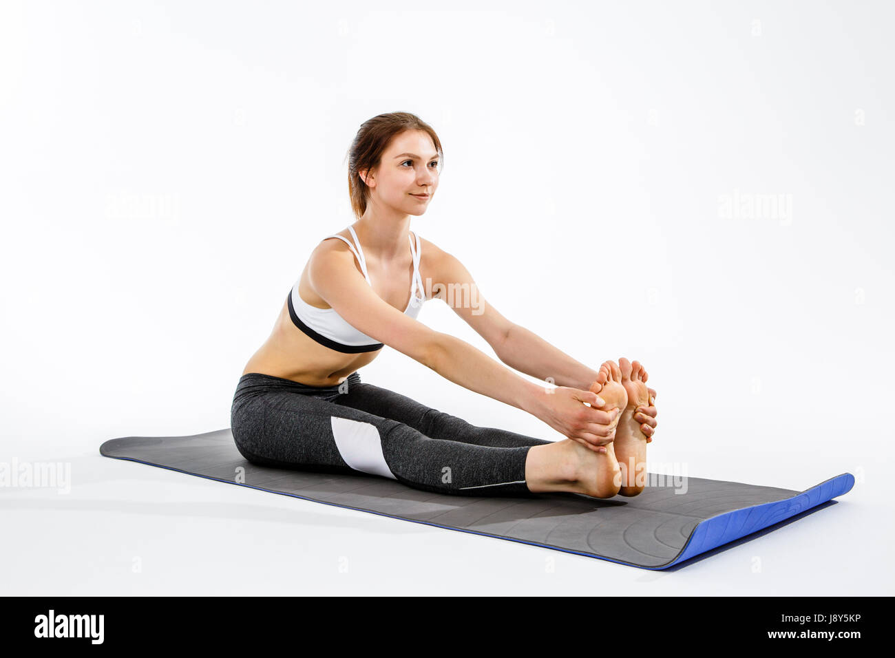 Sportswoman doing stretching on rug at isolated background Stock Photo ...