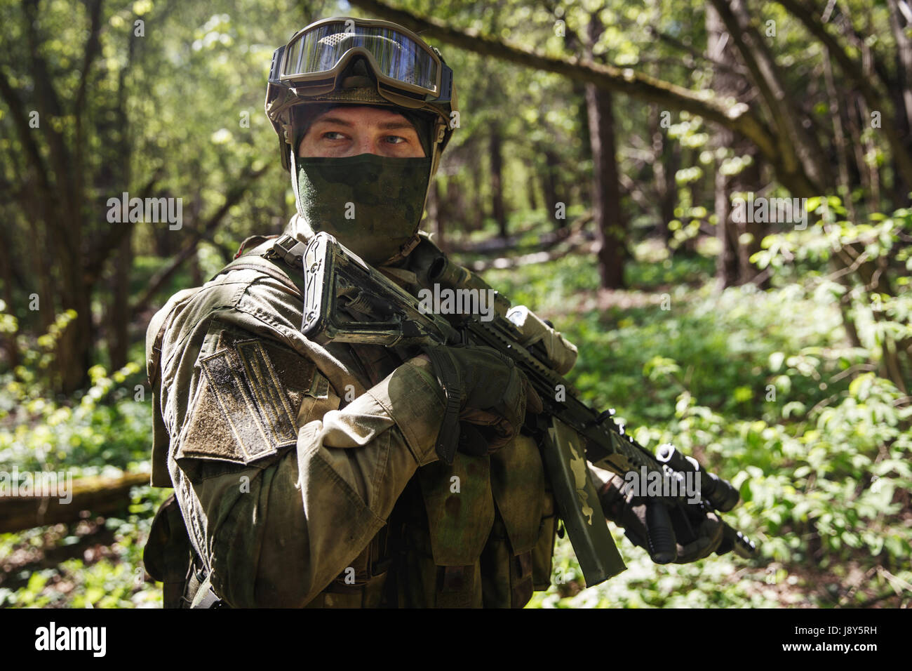 Soldier in mask and helmet on task in woods during day Stock Photo - Alamy