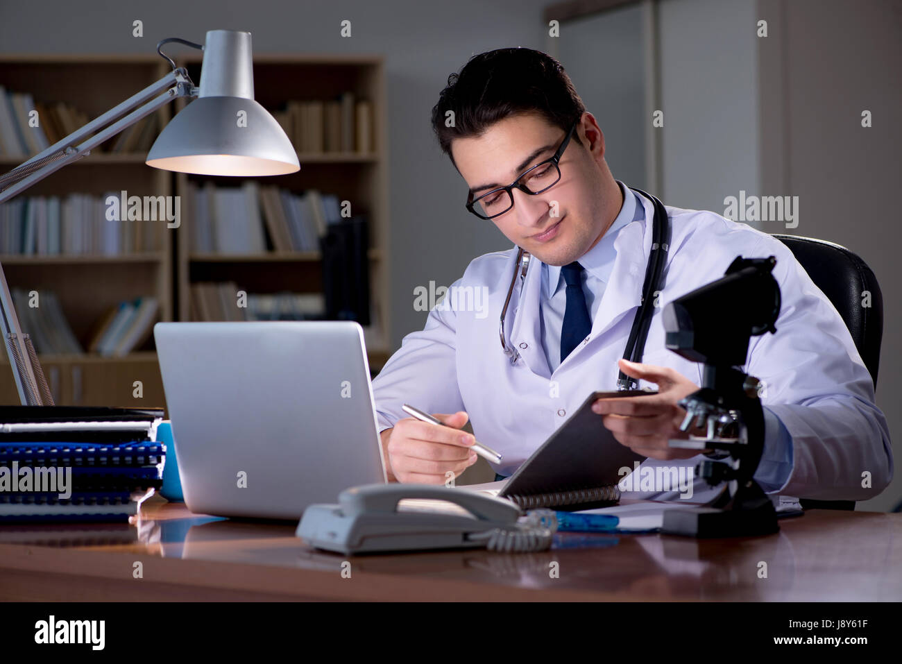Young doctor working late in the office Stock Photo - Alamy