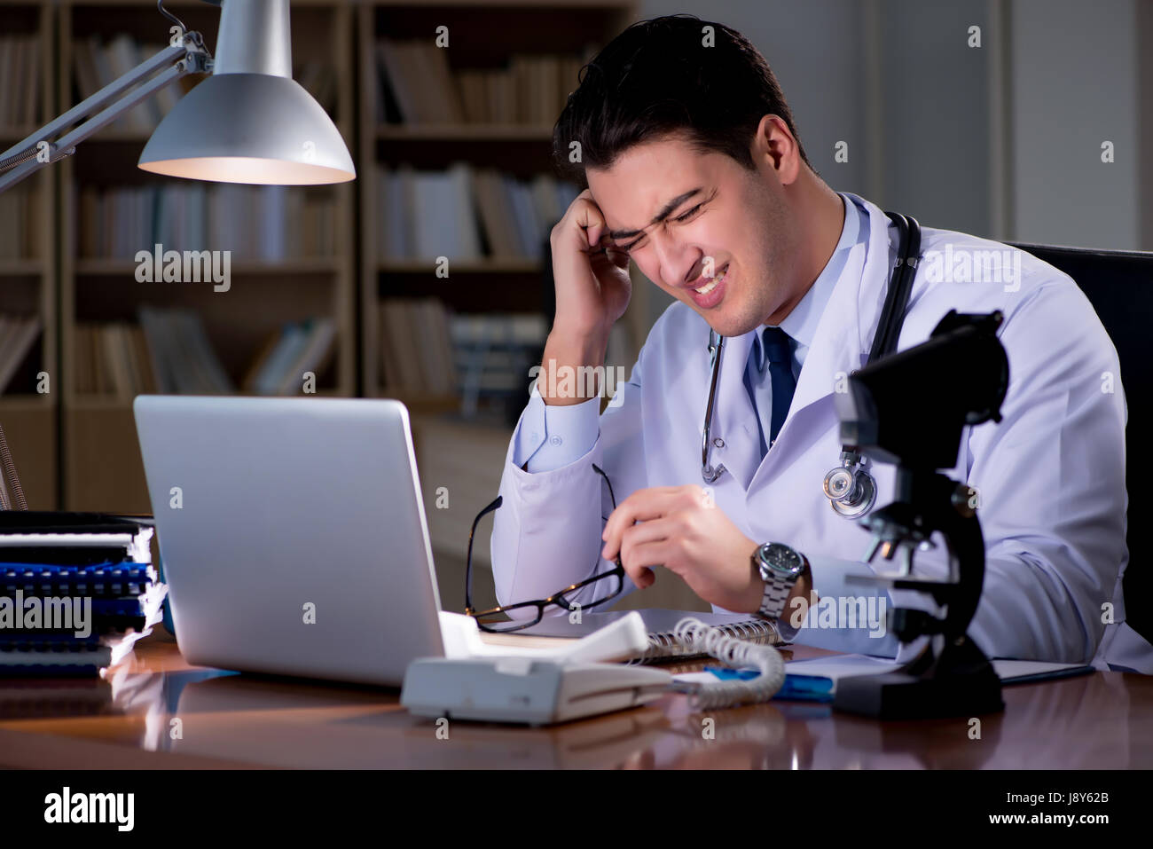 Young doctor working late in the office Stock Photo - Alamy