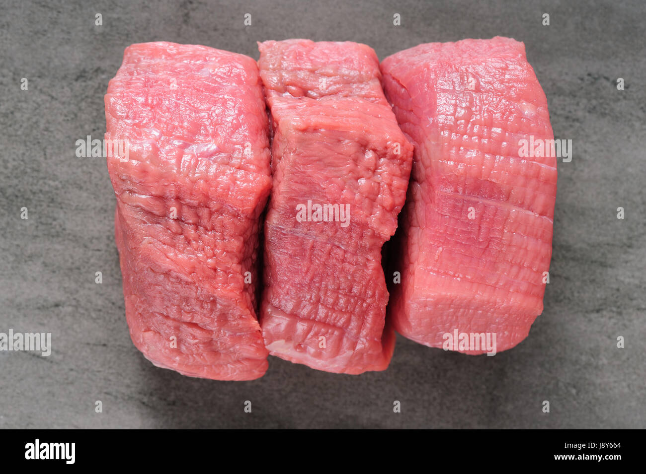 three piecea of raw beef meat on shale board Stock Photo - Alamy