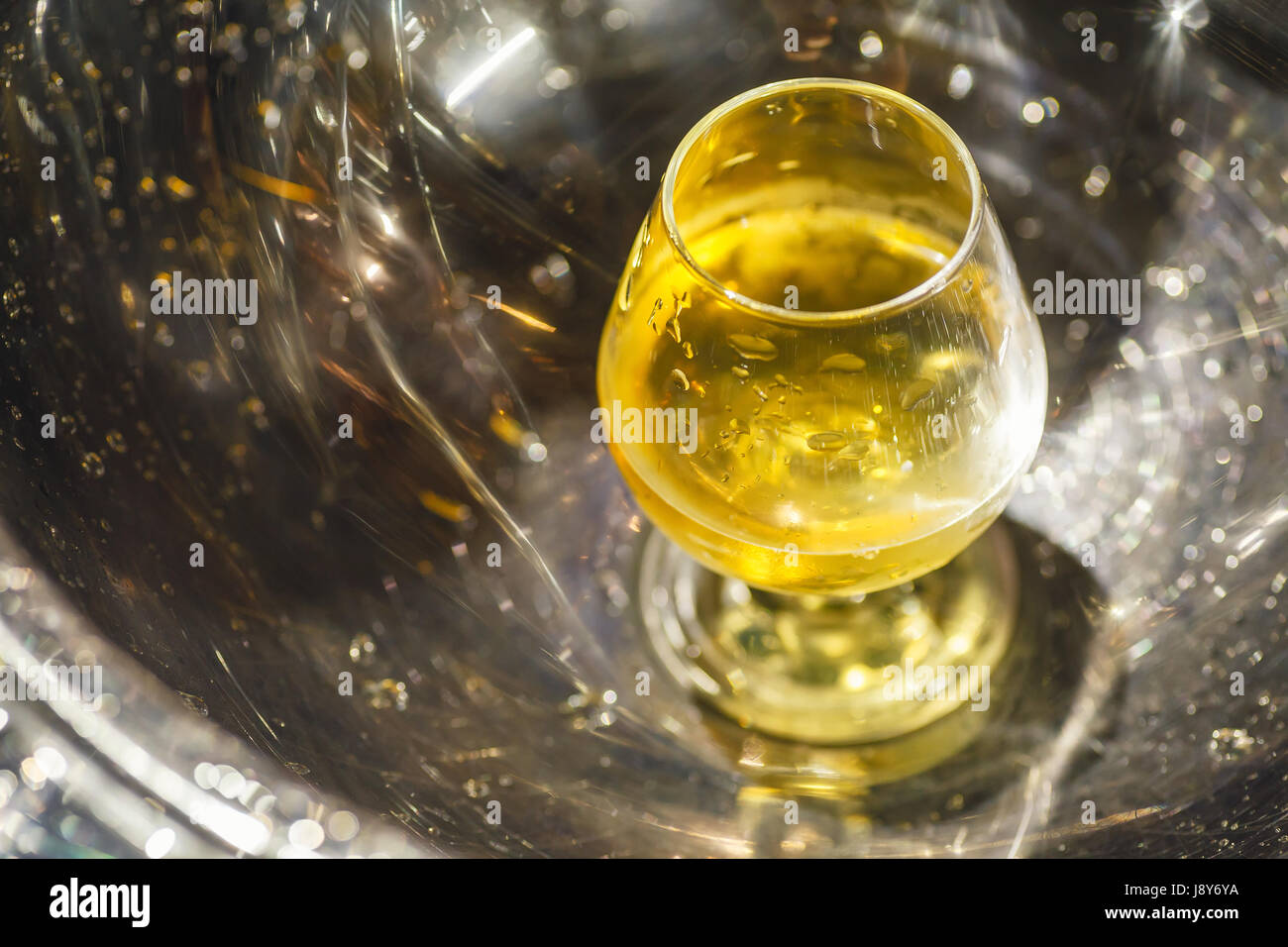 Glass of clear lager beer standing in a small stainless steel sink in a ...