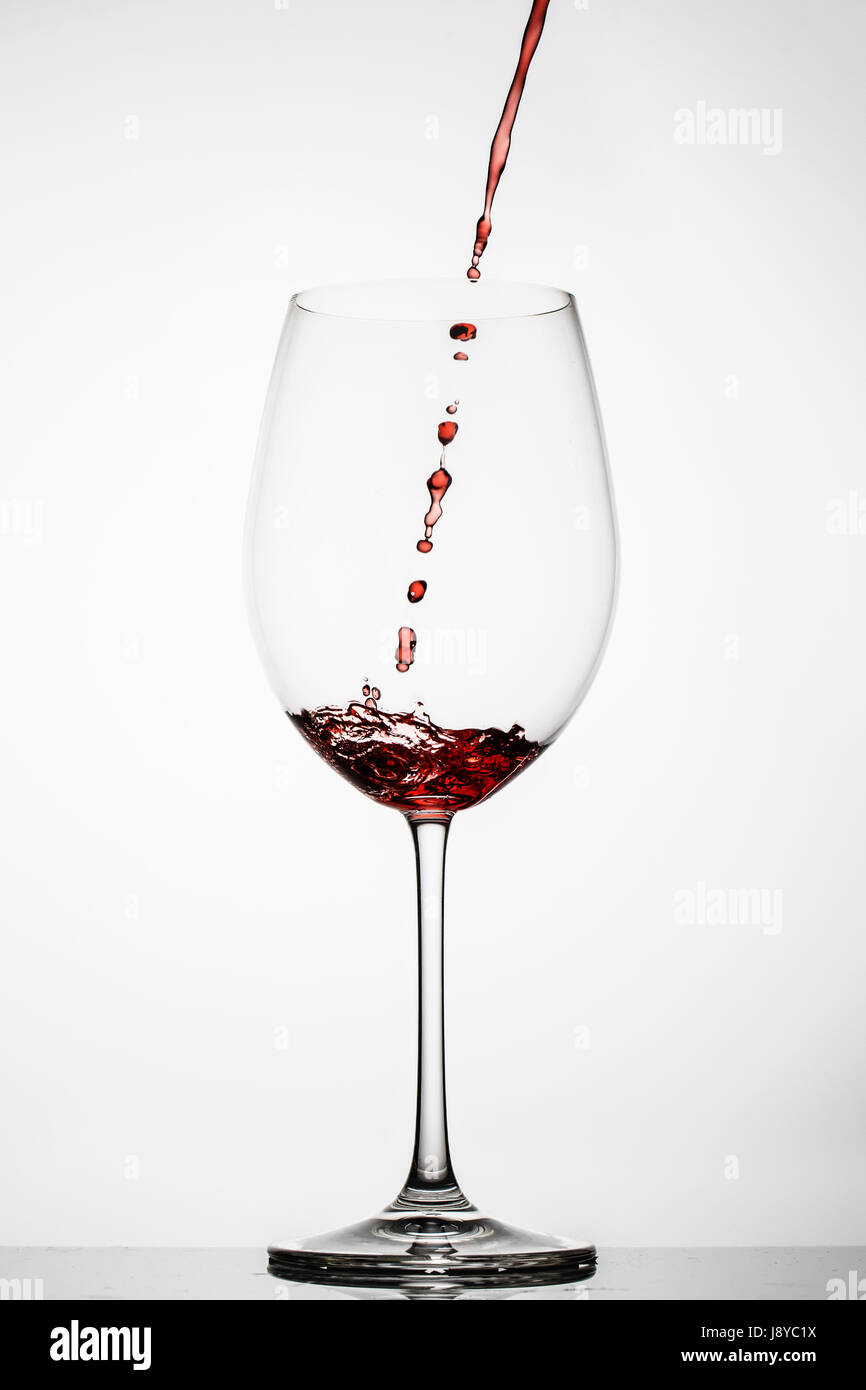 Red wine splashes in a glass on white background Stock Photo - Alamy