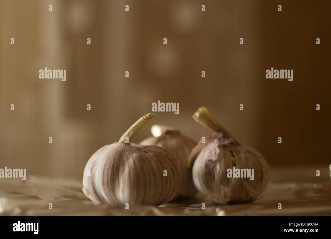 Three heads of brown garlic brown background Stock Photo - Alamy