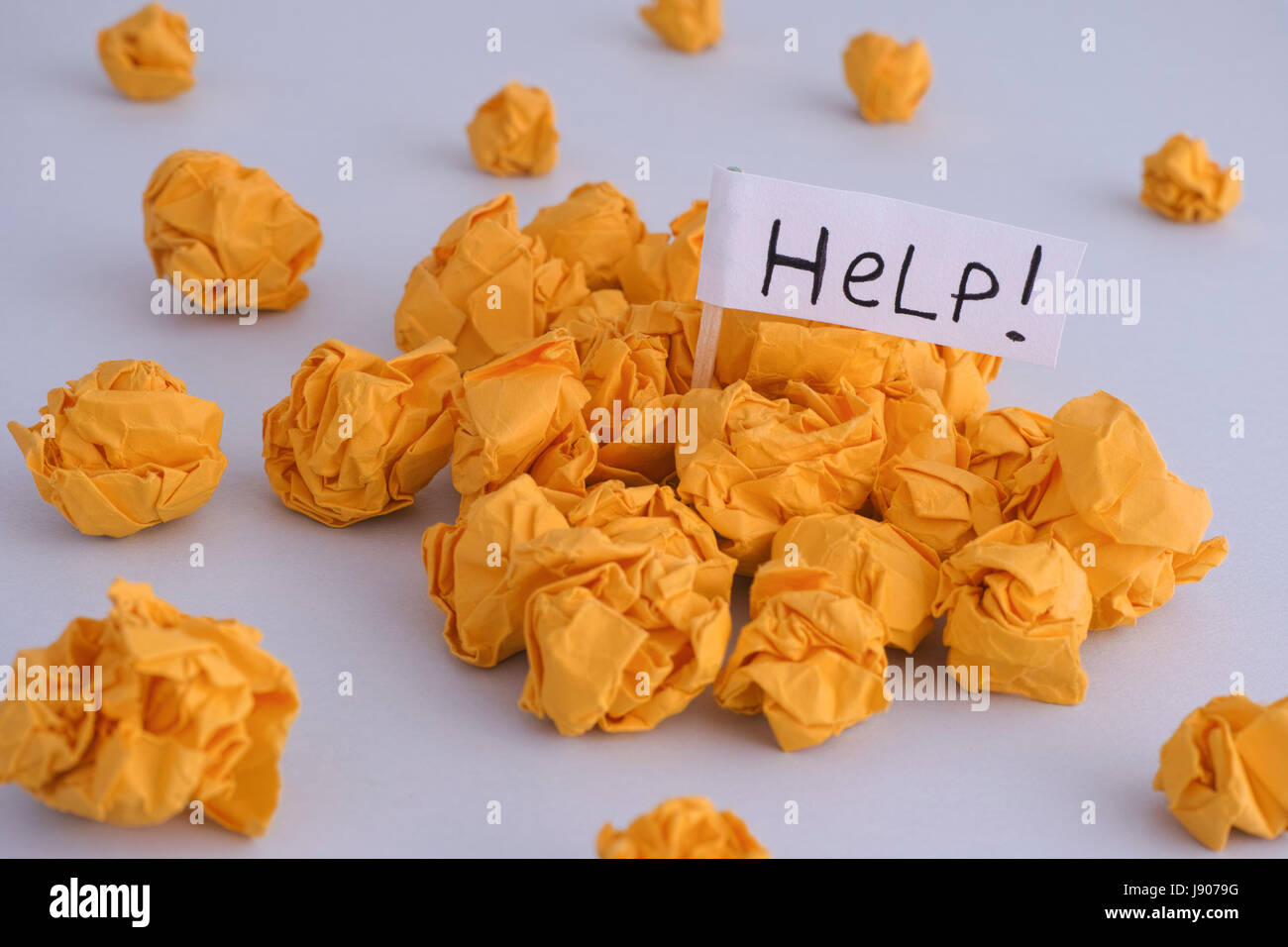 Yellow crumpled paper balls and flag with Help word written on it. Idea ...